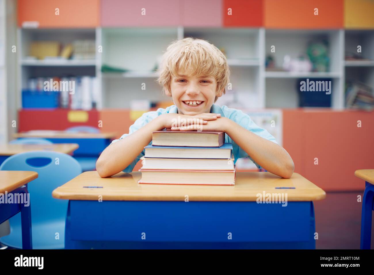 Ive got some reading to do. A happy young boy sitting at his desk and ...