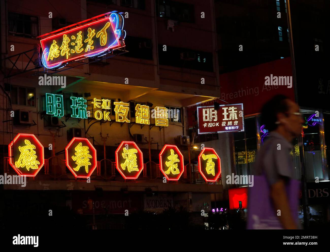In this Aug. 21, 2017, photo, a man walks past some neon signs at a ...