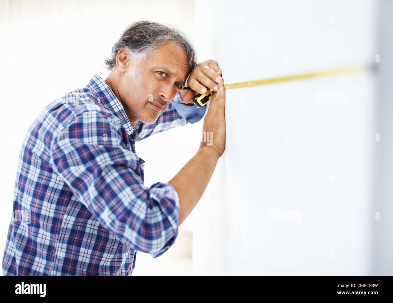 Architect measuring wall with masking tape. Handsome mature architect ...