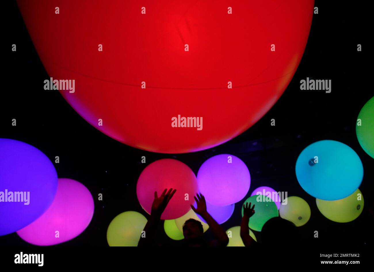 Visitors reach out for colorful balloons "Sound Spheres" as they enjoy ...