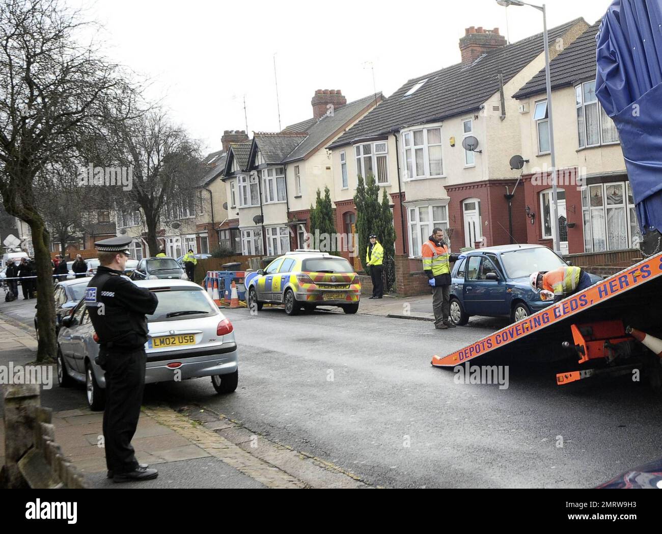 Police stand guard while neighbors and reporters gather at the Luton ...