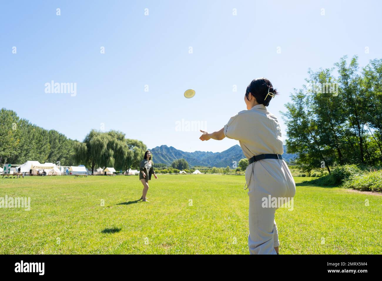 Two people at the campsite play frisbee Stock Photo - Alamy