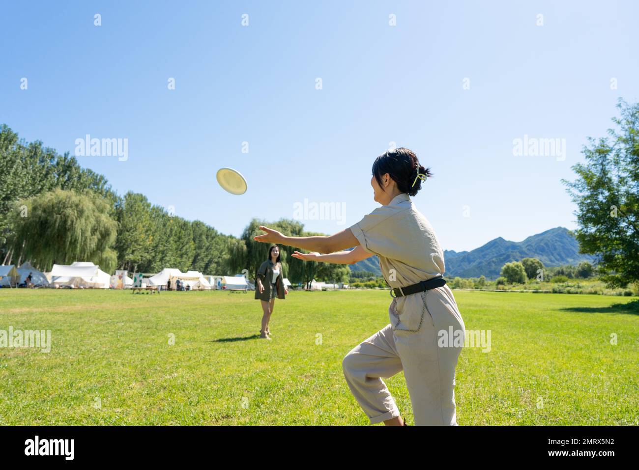 Two people at the campsite play frisbee Stock Photo - Alamy
