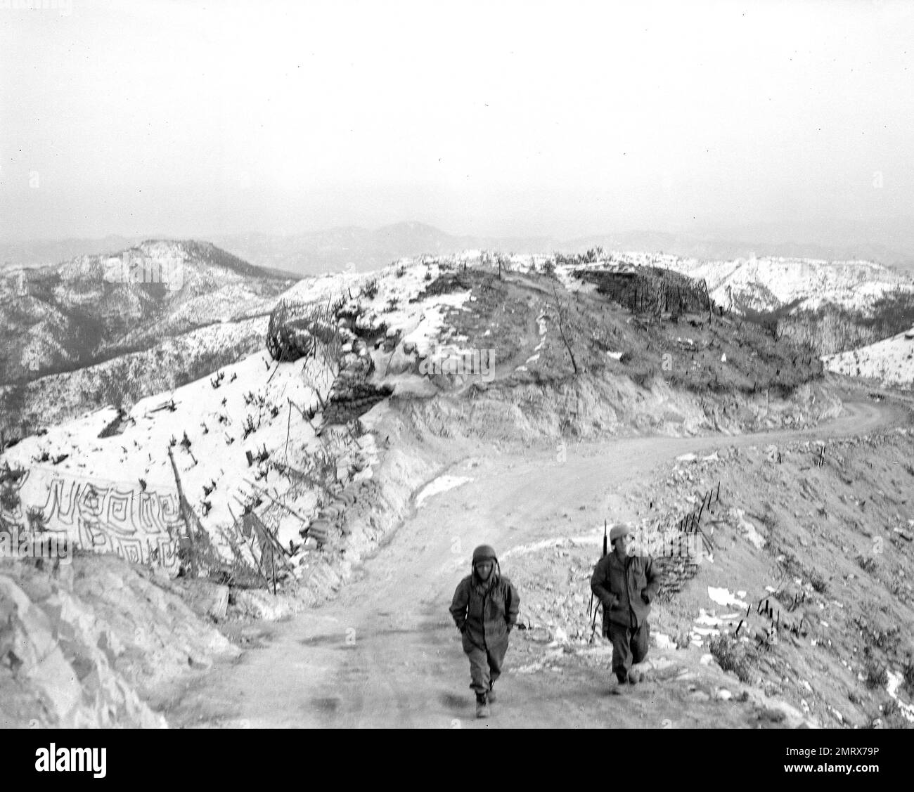 Two GIs move up the cold snow-covered road toward their front line ...
