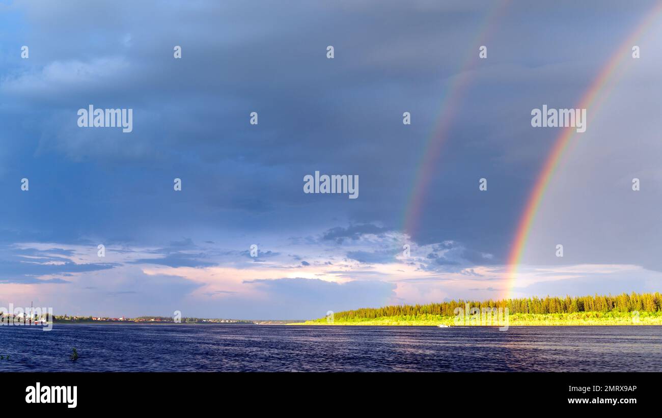 A double rainbow over the river against the backdrop of clouds and ...