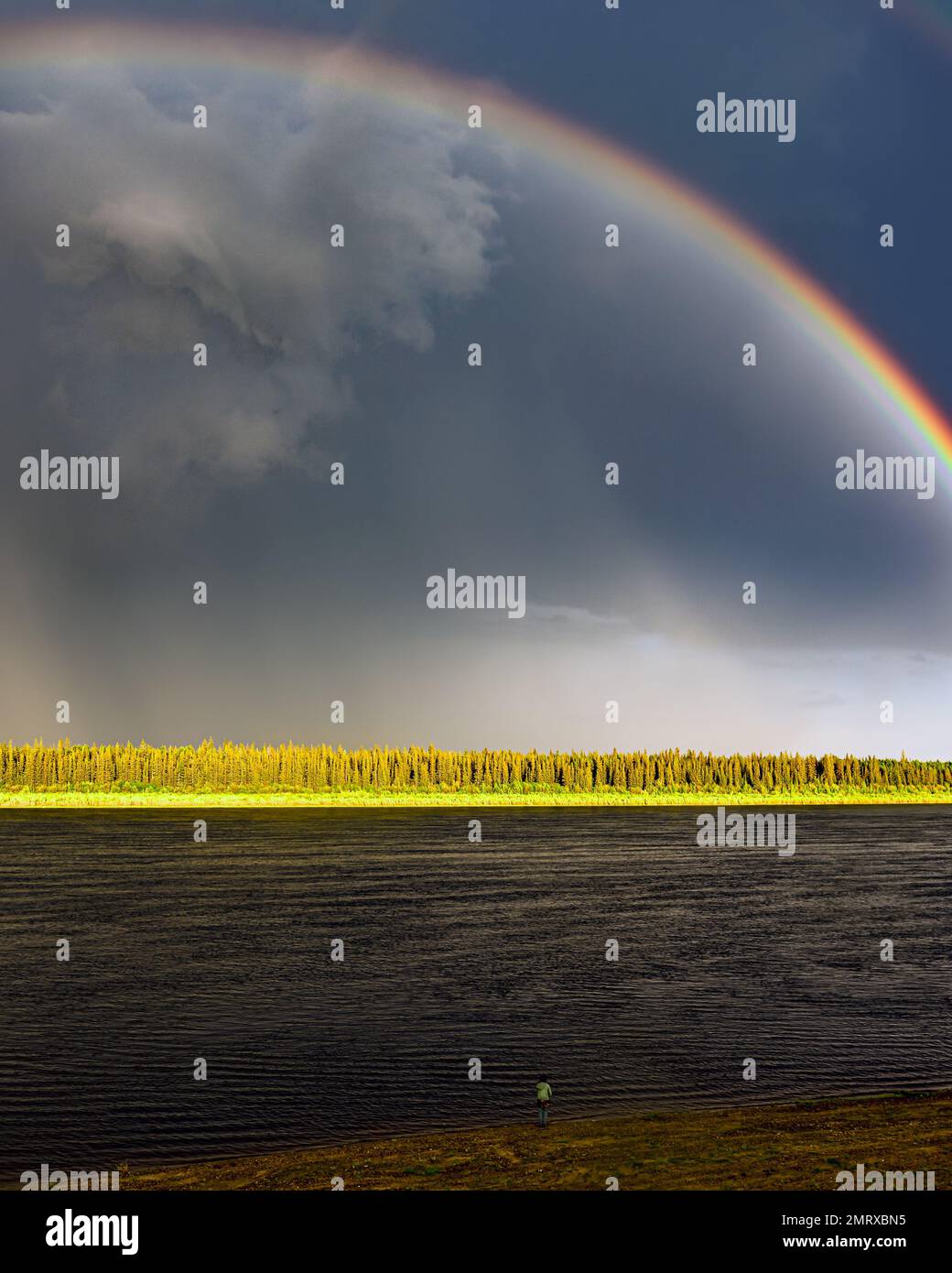 A bright double rainbow after rain during the day over a river against ...
