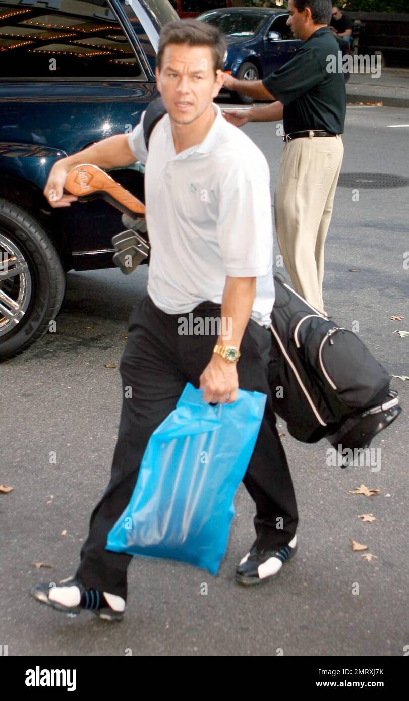 Mark Wahlberg, clad in his golf attire with clubs in tow, greets and ...