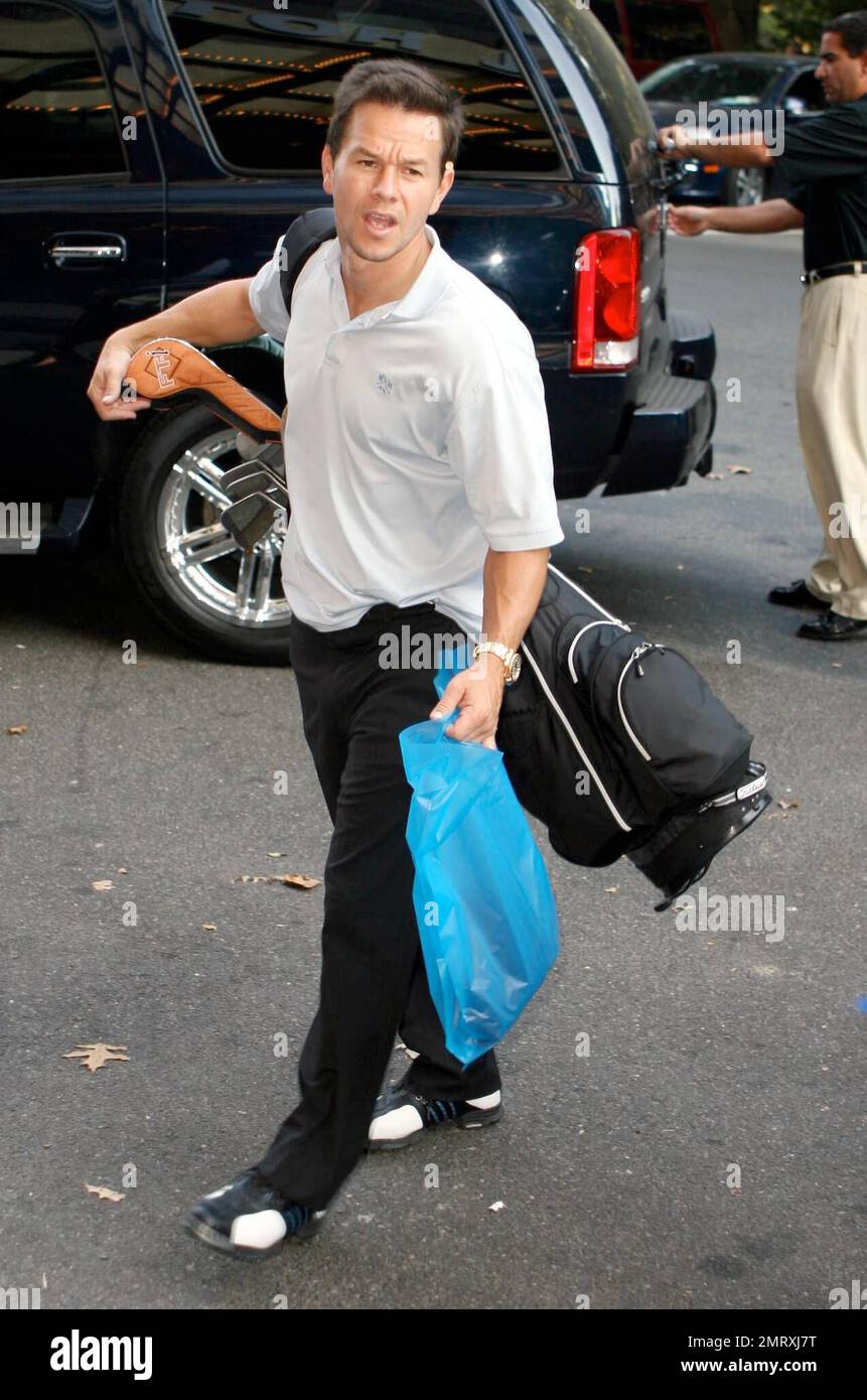 Mark Wahlberg, clad in his golf attire with clubs in tow, greets and ...