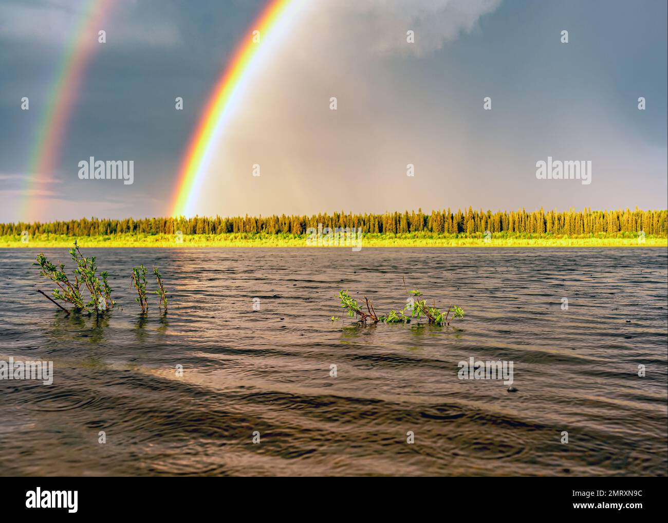 Double rainbow over the Vilyui River with raindrops against a blue sky ...