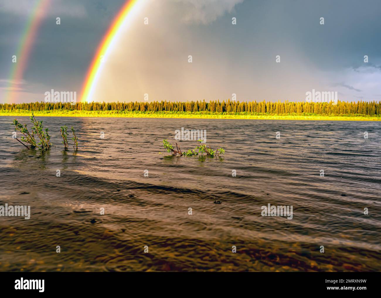 A double rainbow over the Vilyui River with raindrops against a blue ...