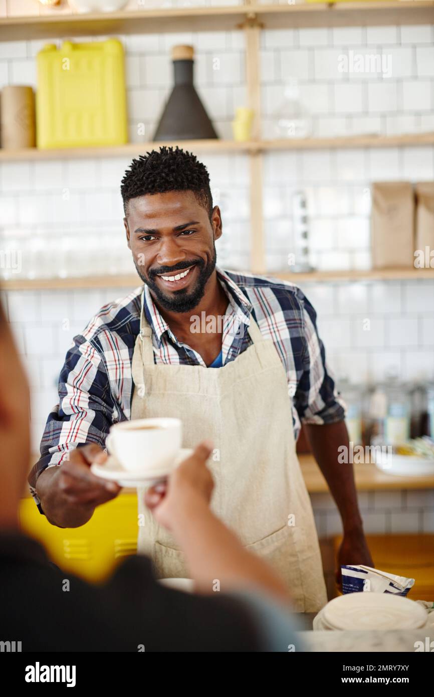 Giving you some happiness in a cup. a handsome young man serving a ...