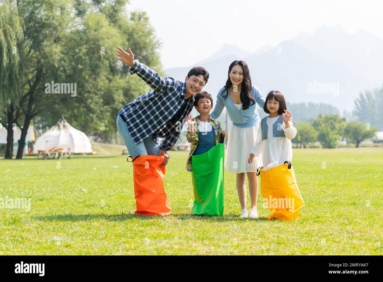 A family of four happy play games on the grass Stock Photo - Alamy