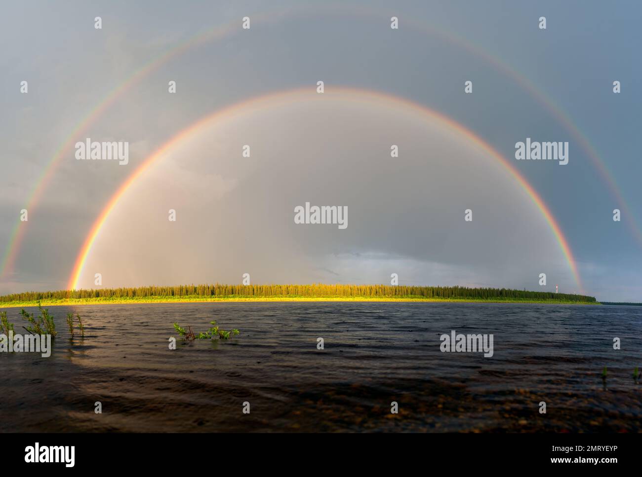 Panorama of a full double rainbow against the background of a dark blue ...