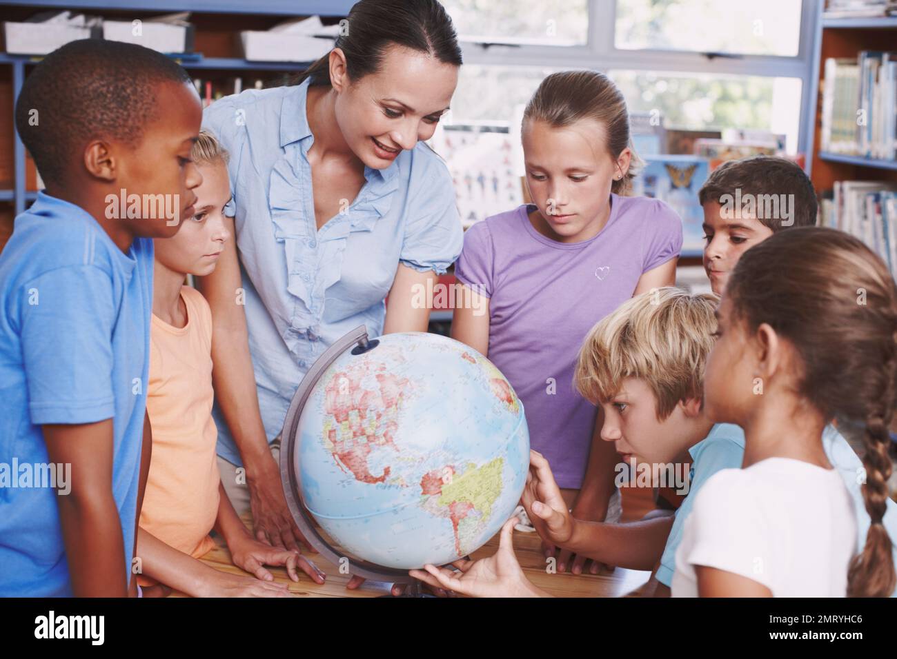 The world is so big. A pretty young geography teacher teaching her ...