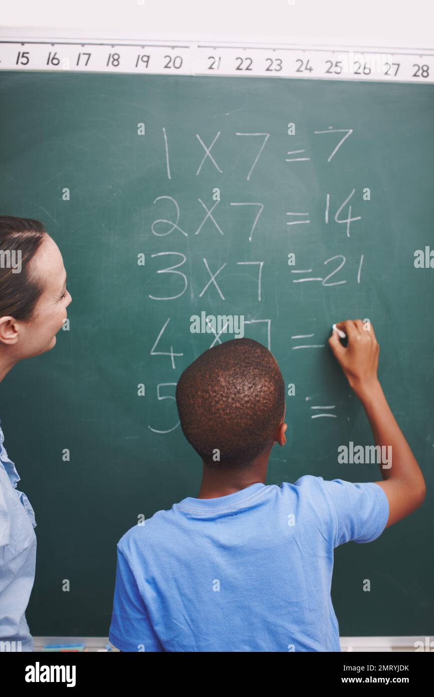 Helping him reach his potential. Rear view of a young boy doing his ...