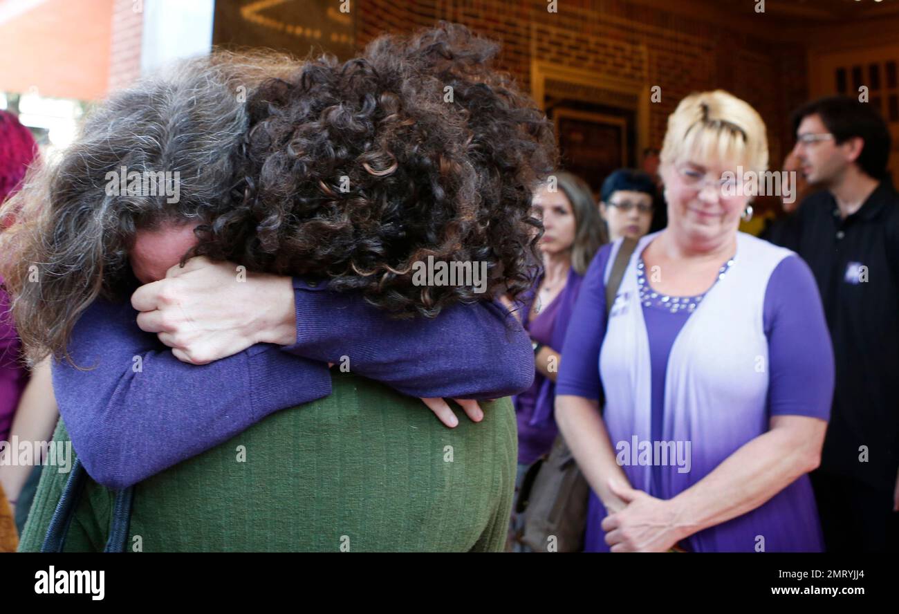 Women embrace outside the Paramount Theater after a memorial service ...
