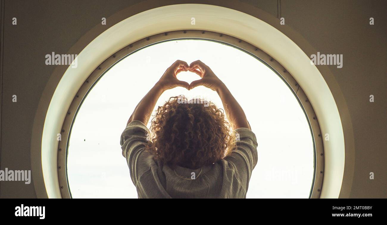 Back view of a woman doing heart sign gesture with hands in a circle ...