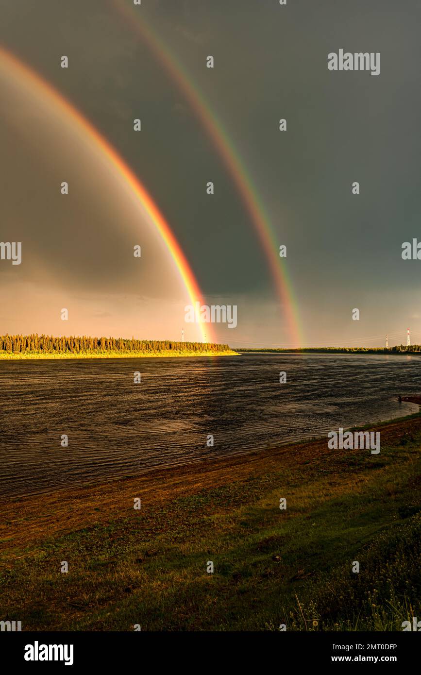 A double rainbow against a dark sky emerges from power pylons and ...