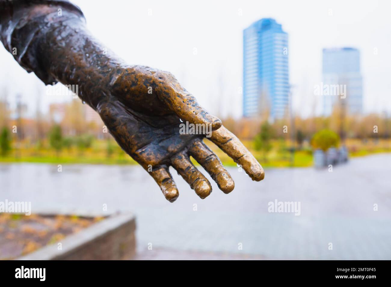 Male hand palm bronze sculpture in rain gives hand, help concept. Close ...