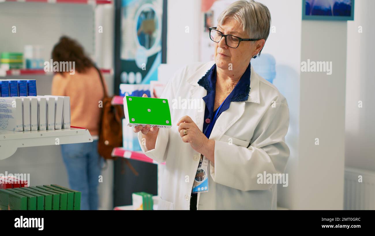 Woman pharmacist holding box of pills with greenscreen, working in ...