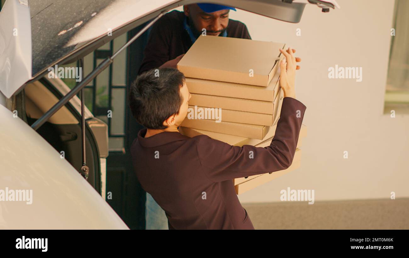Food delivery worker giving pizza boxes to clients at office entrance ...
