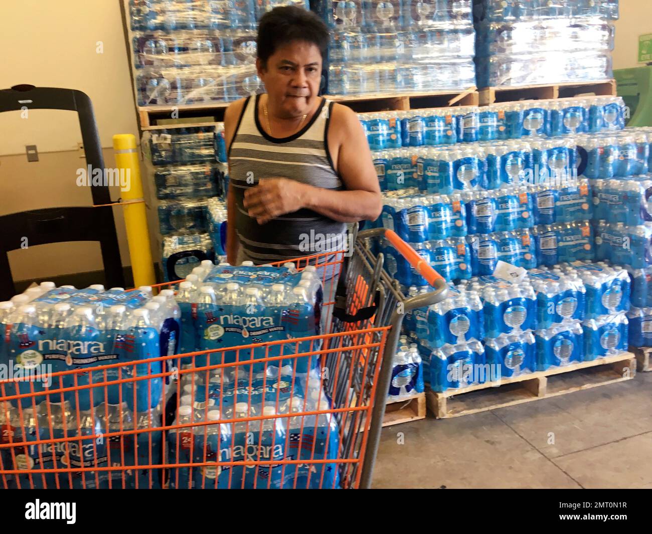 A resident buys bottles of water at Home Depot in Guam Saturday, Aug ...