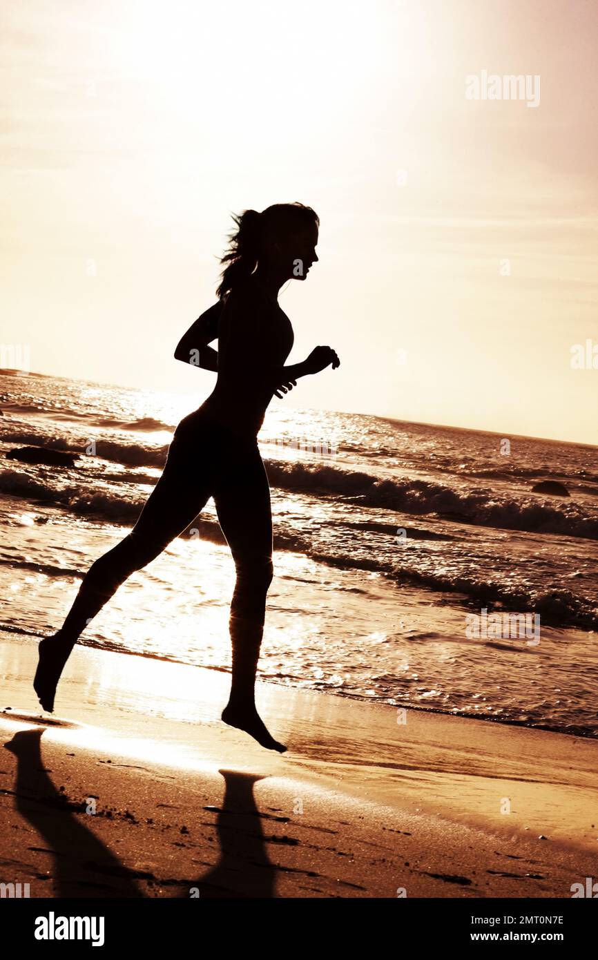 Young female running during sunset on beach. Portrait of a young female ...