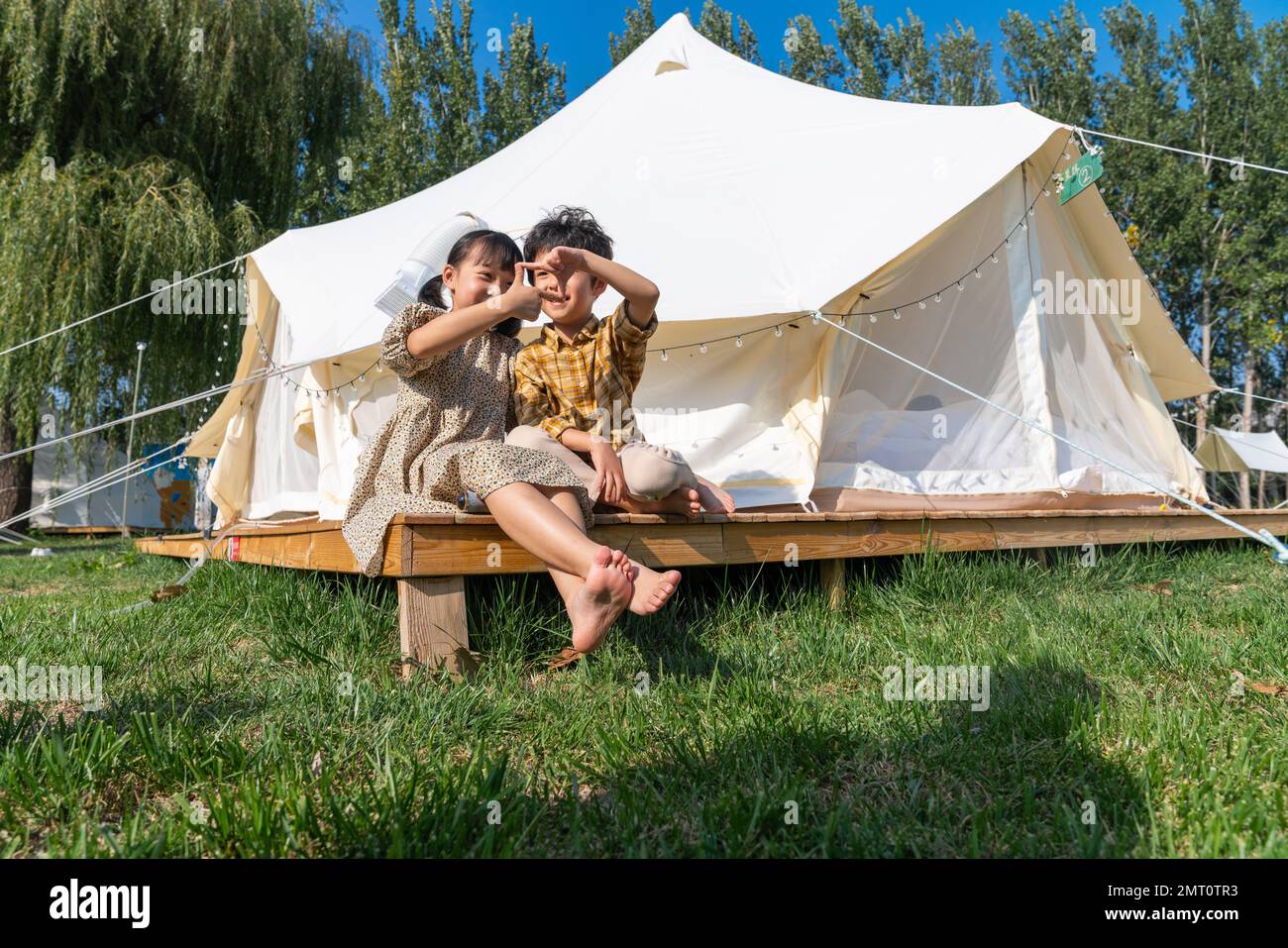 The two children playing sat outside the tent Stock Photo - Alamy