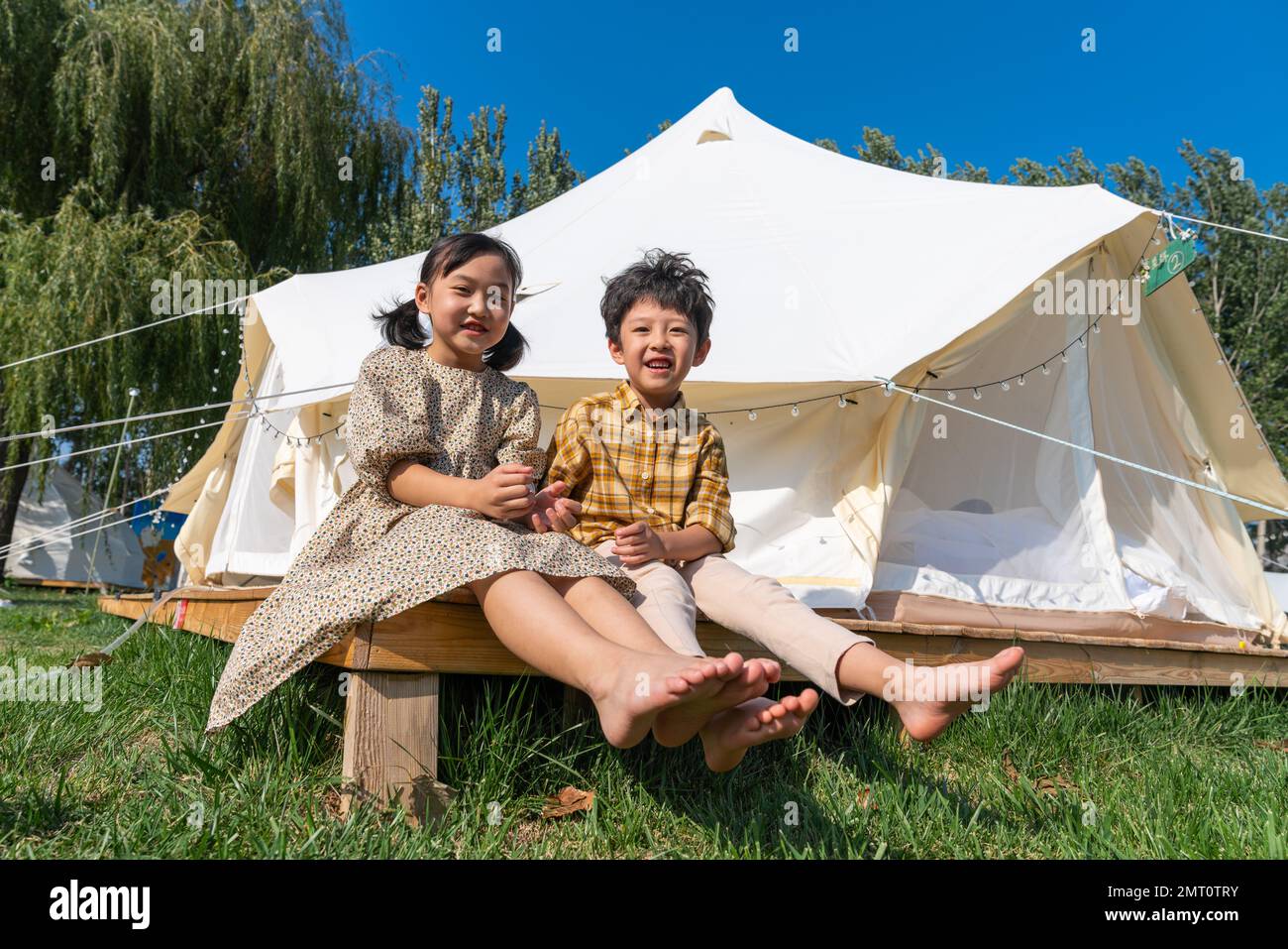 The two children playing sat outside the tent Stock Photo - Alamy