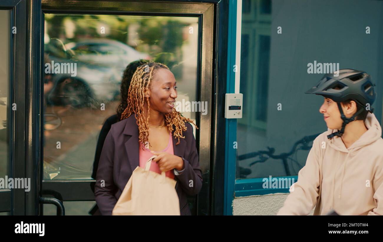 Female carrier giving fastfood package order to woman at office ...