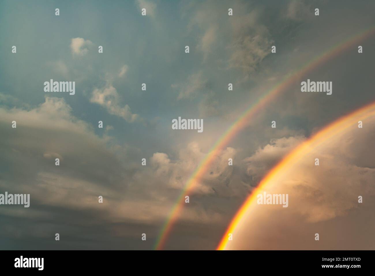 Two rainbows against the background of a dark blue sky and clouds after the rain in the evening ...