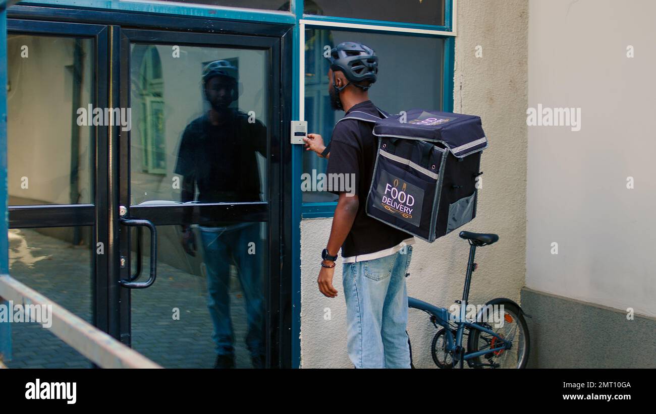 Smiling courier giving client paper bag with fastfood order, office ...