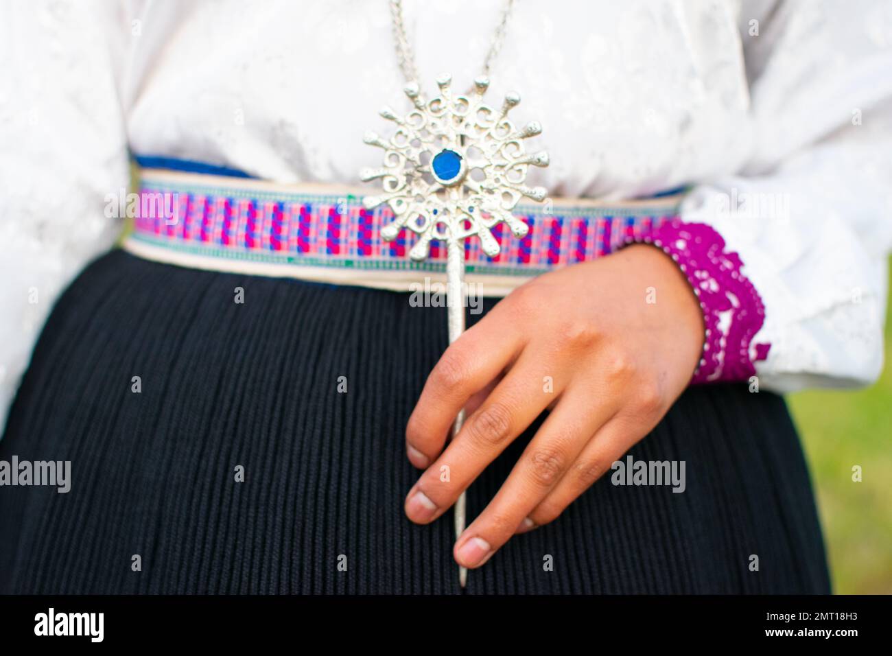A Traditional Saraguro women's silver jewelry in a woman's hand with a ...