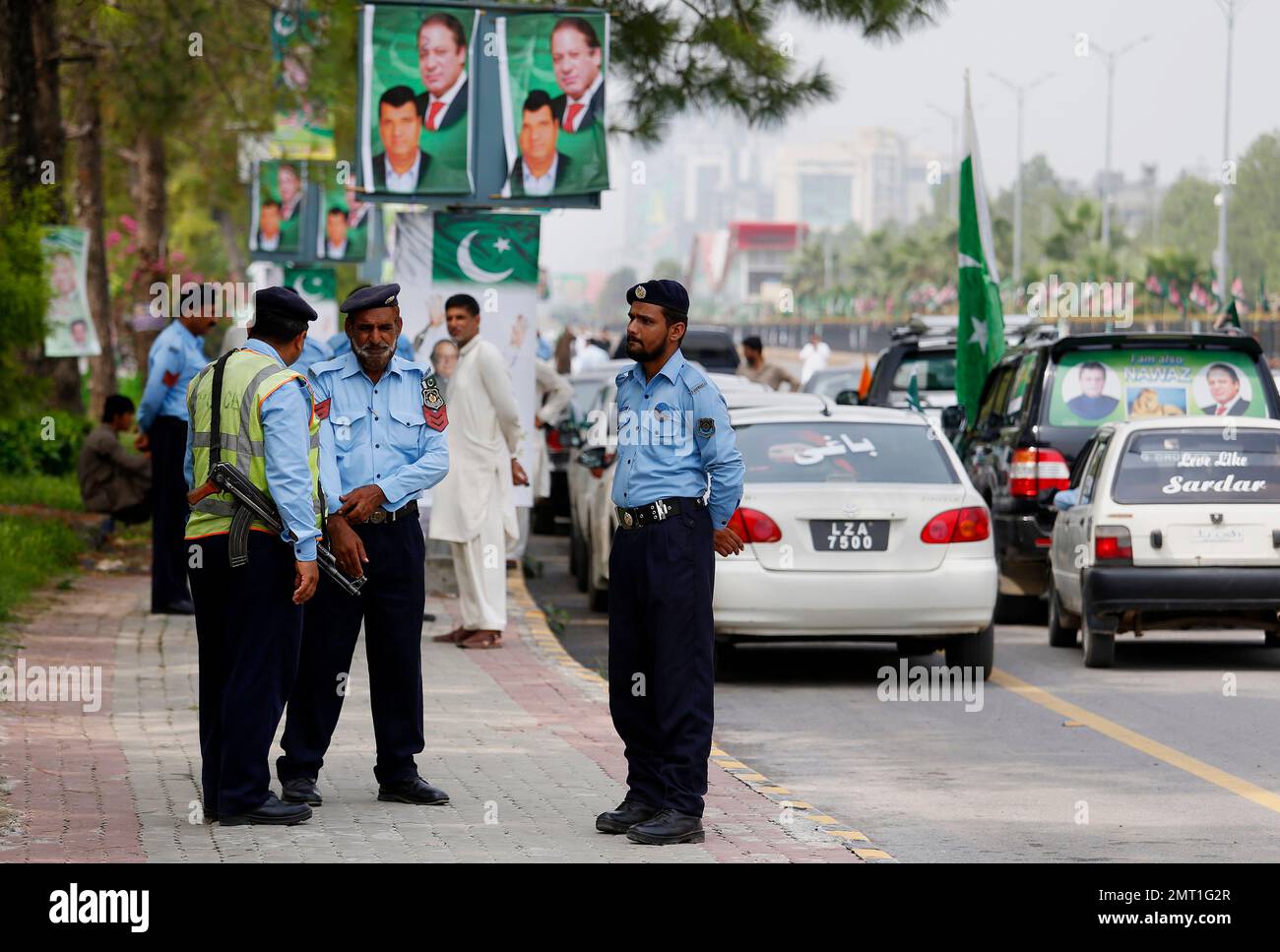 Pakistani police officers stand guard next to the posters of Pakistan's ...
