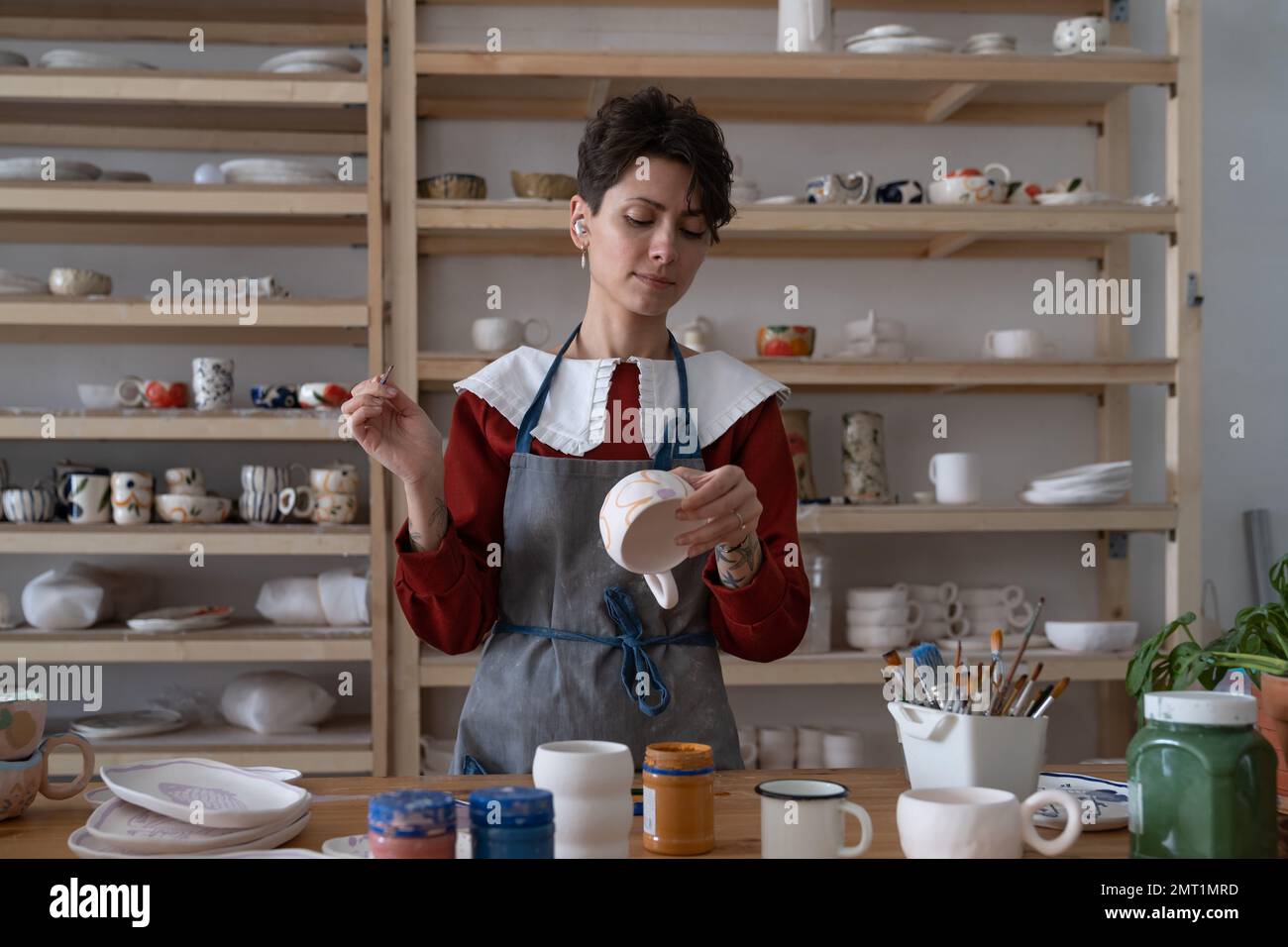 Concentrated young woman professional pottery artisan work in studio ...