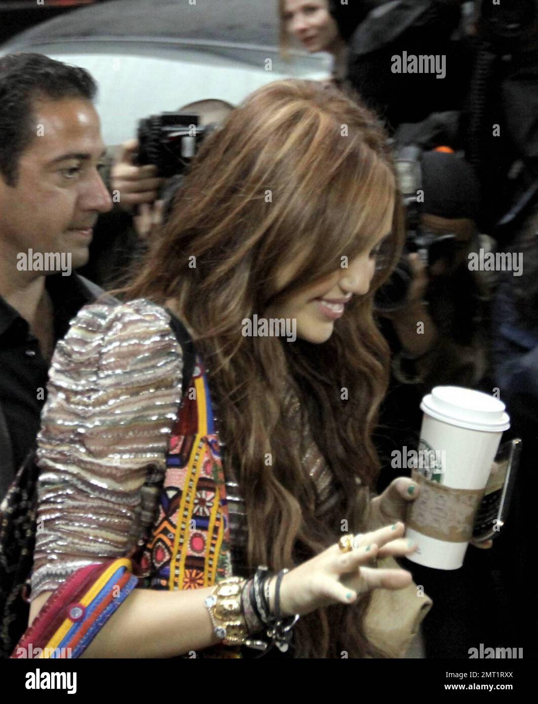 Miley Cyrus brings along a Starbuck's coffee as she arrives with sister ...