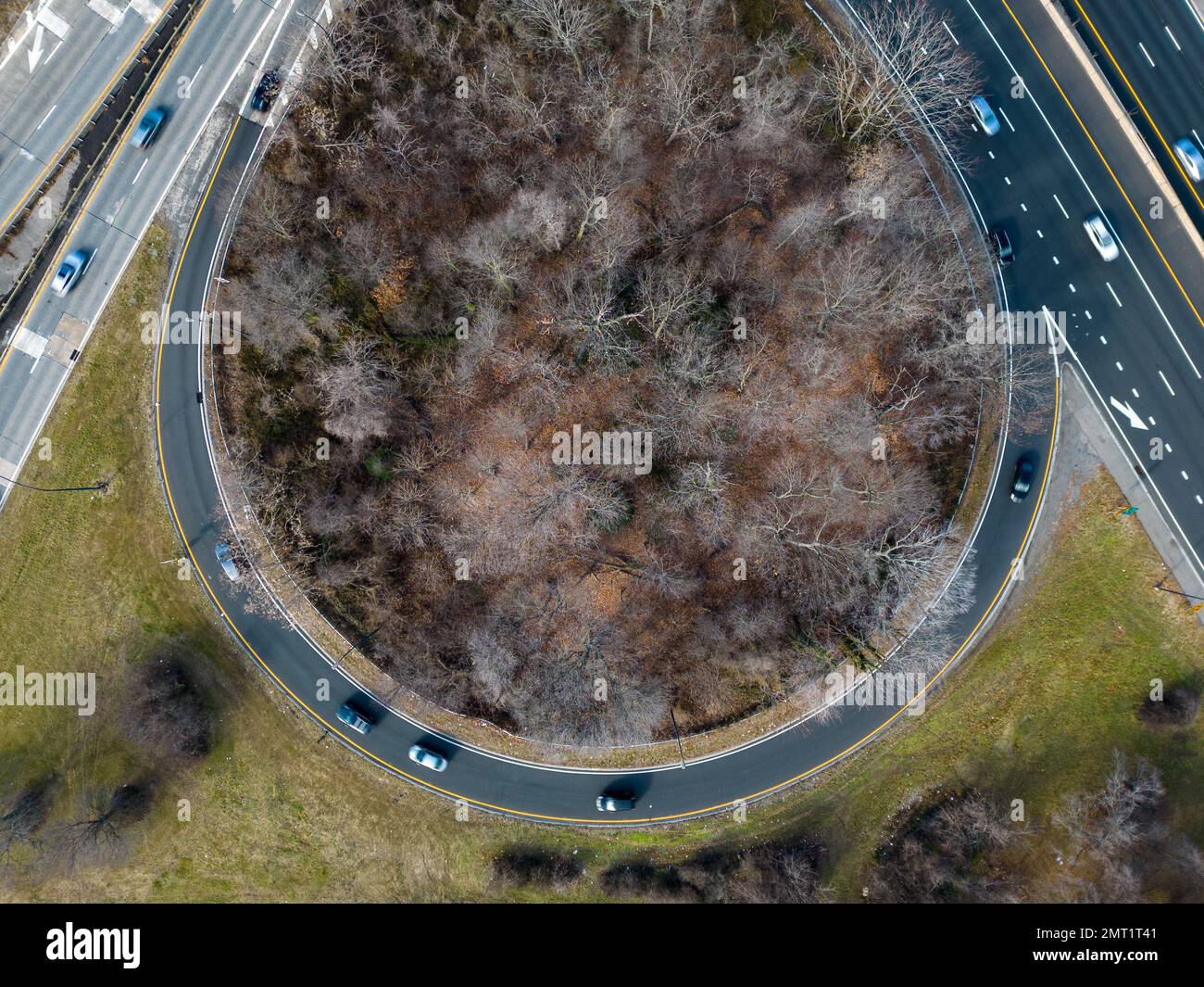 A droe shot over cars on circle road with garden ad gree spaces in the ...