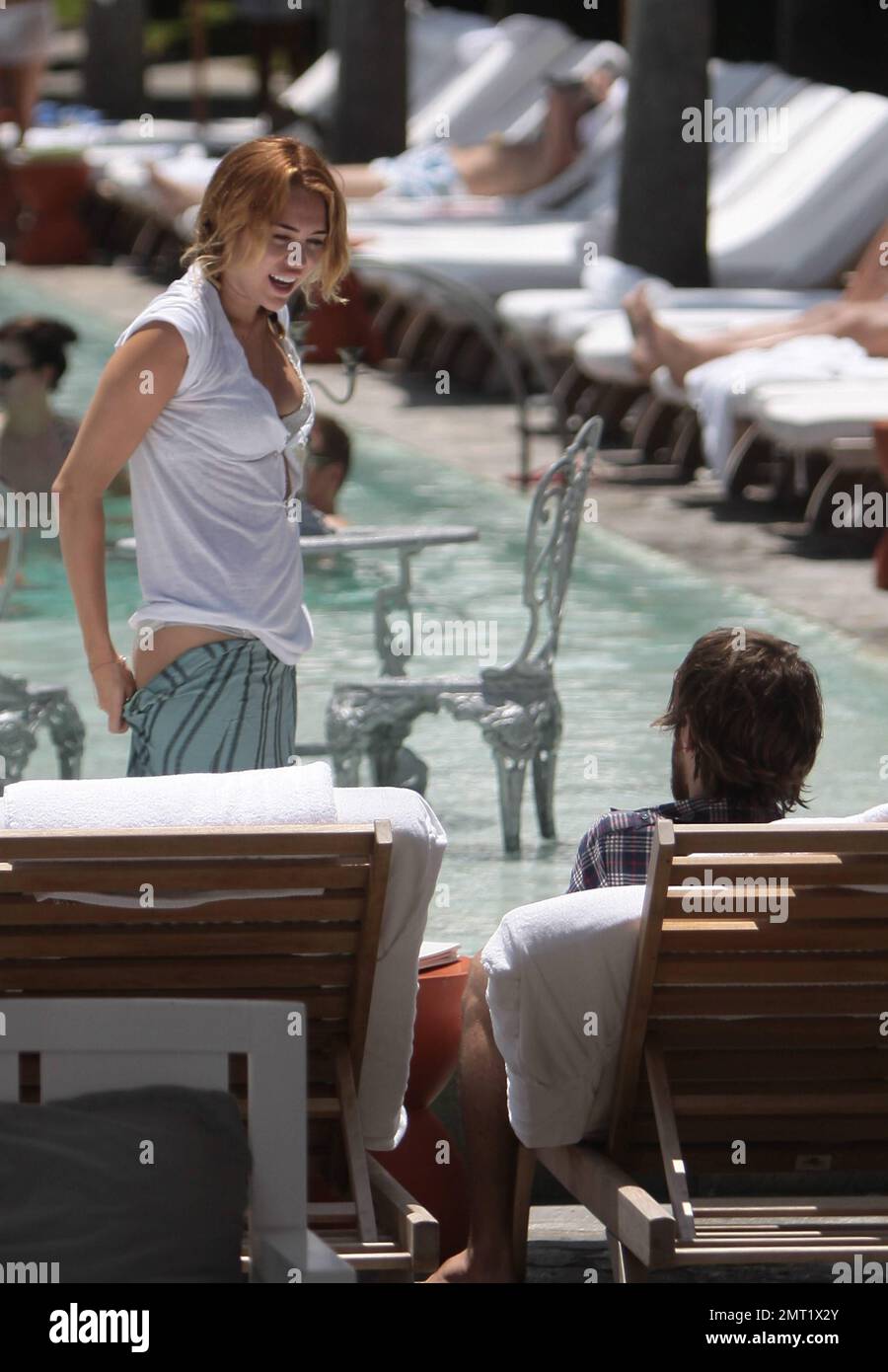 Singer Miley Cyrus spends the day with a friend floating in the pool ...