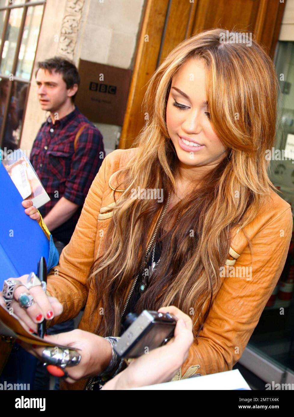 Miley Cyrus signs autographs for fans as she leaves the BBC after an ...