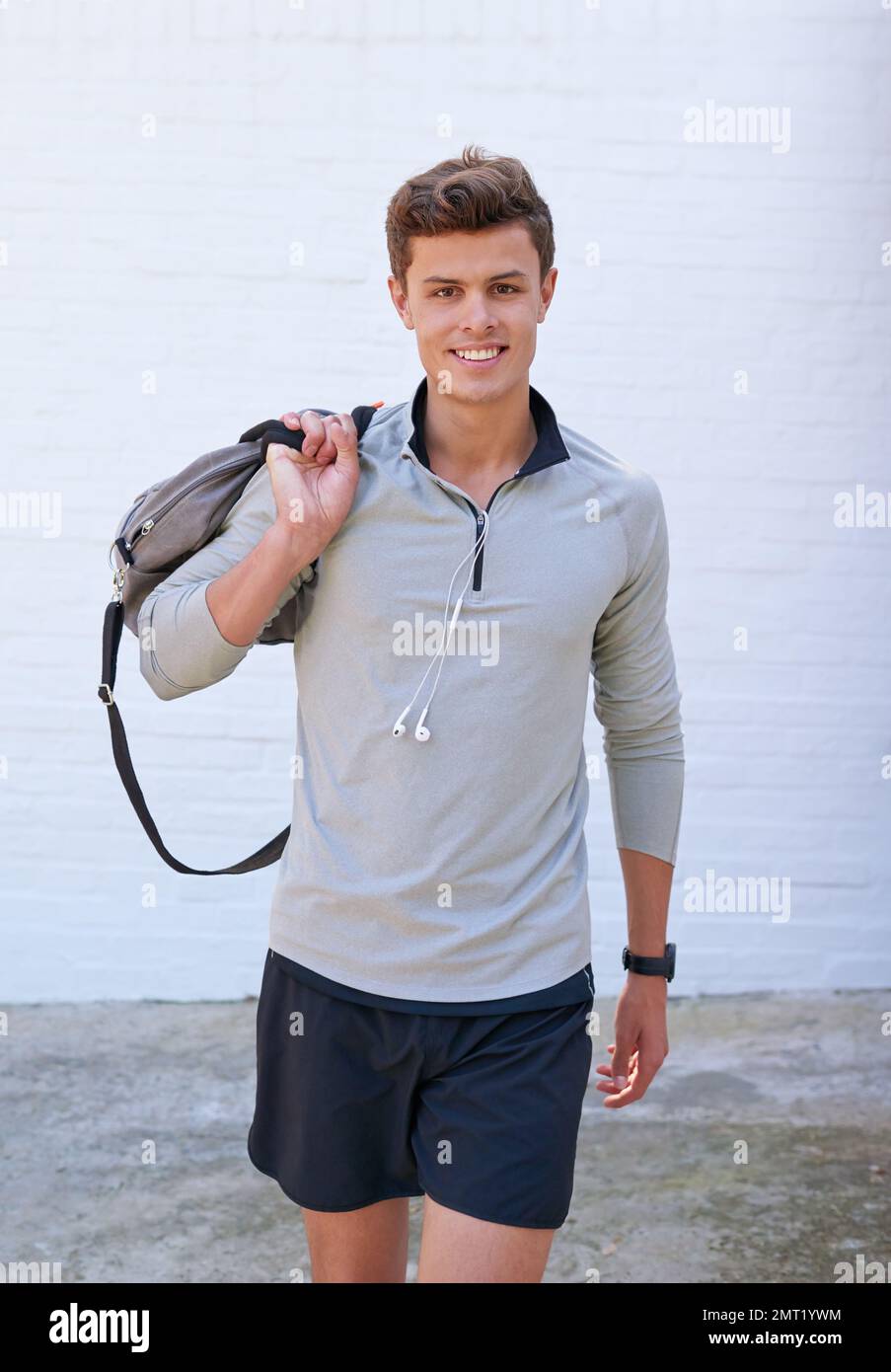 Its time for my gym session. a handsome young man holding his gym bag ...