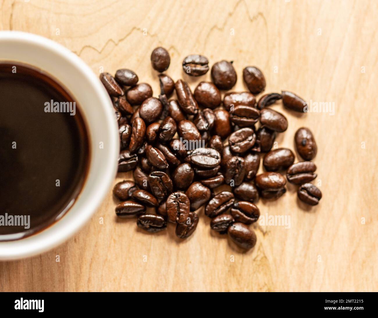 A top view shot of a bunch of coffee beans and a half full coffee cup ...