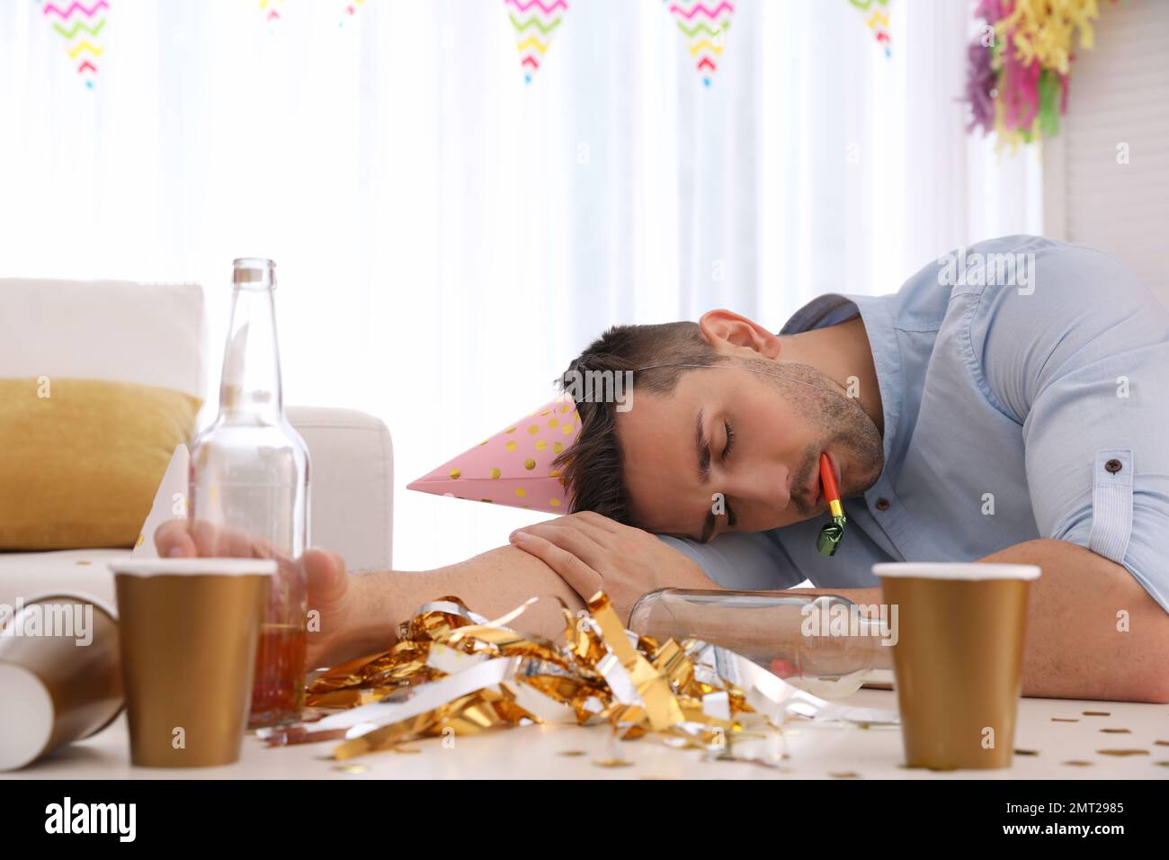 Young man with festive cap sleeping at table after party Stock Photo ...