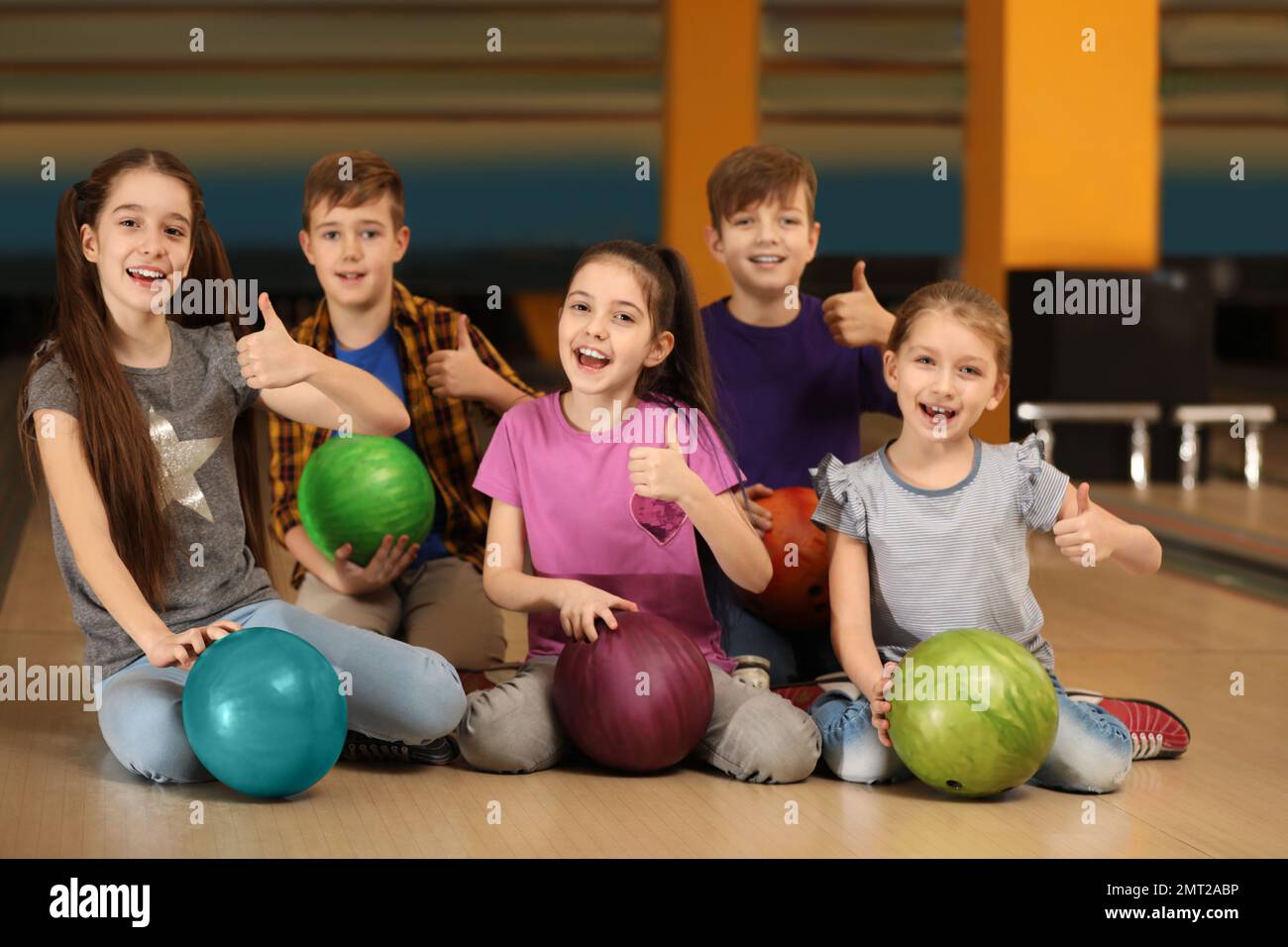 Happy children with balls in bowling club Stock Photo - Alamy