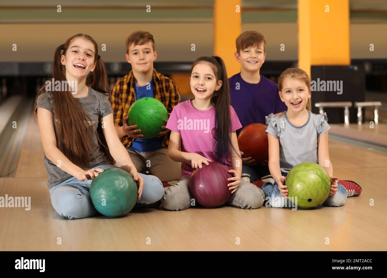 Happy children with balls in bowling club Stock Photo - Alamy
