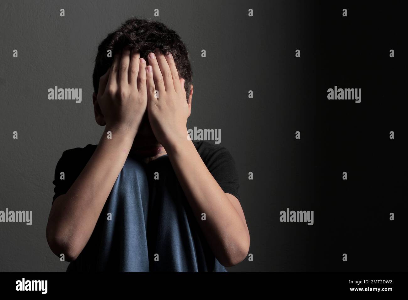 A boy covering his face to hide his tears, the concept of childhood ...
