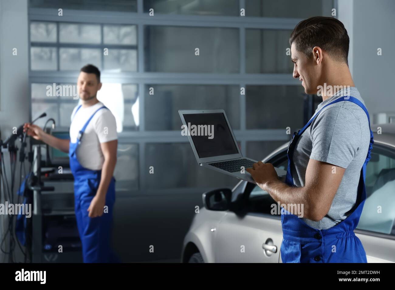 Mechanic with laptop doing car diagnostic at automobile repair shop ...
