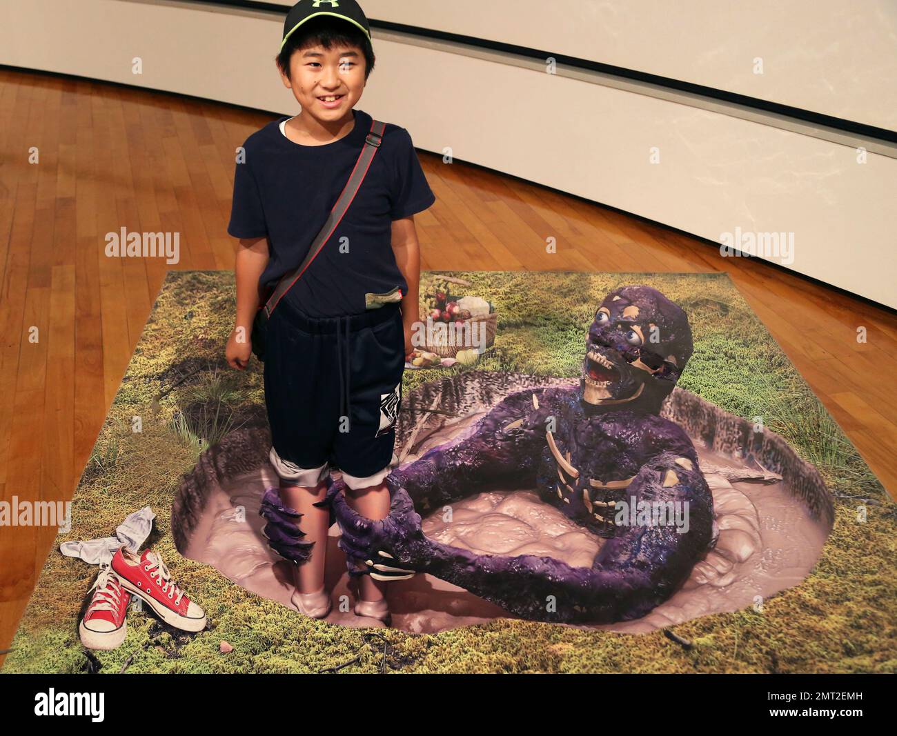 A boy poses with a 3D image at a 3D trick art exhibition by Japanese ...