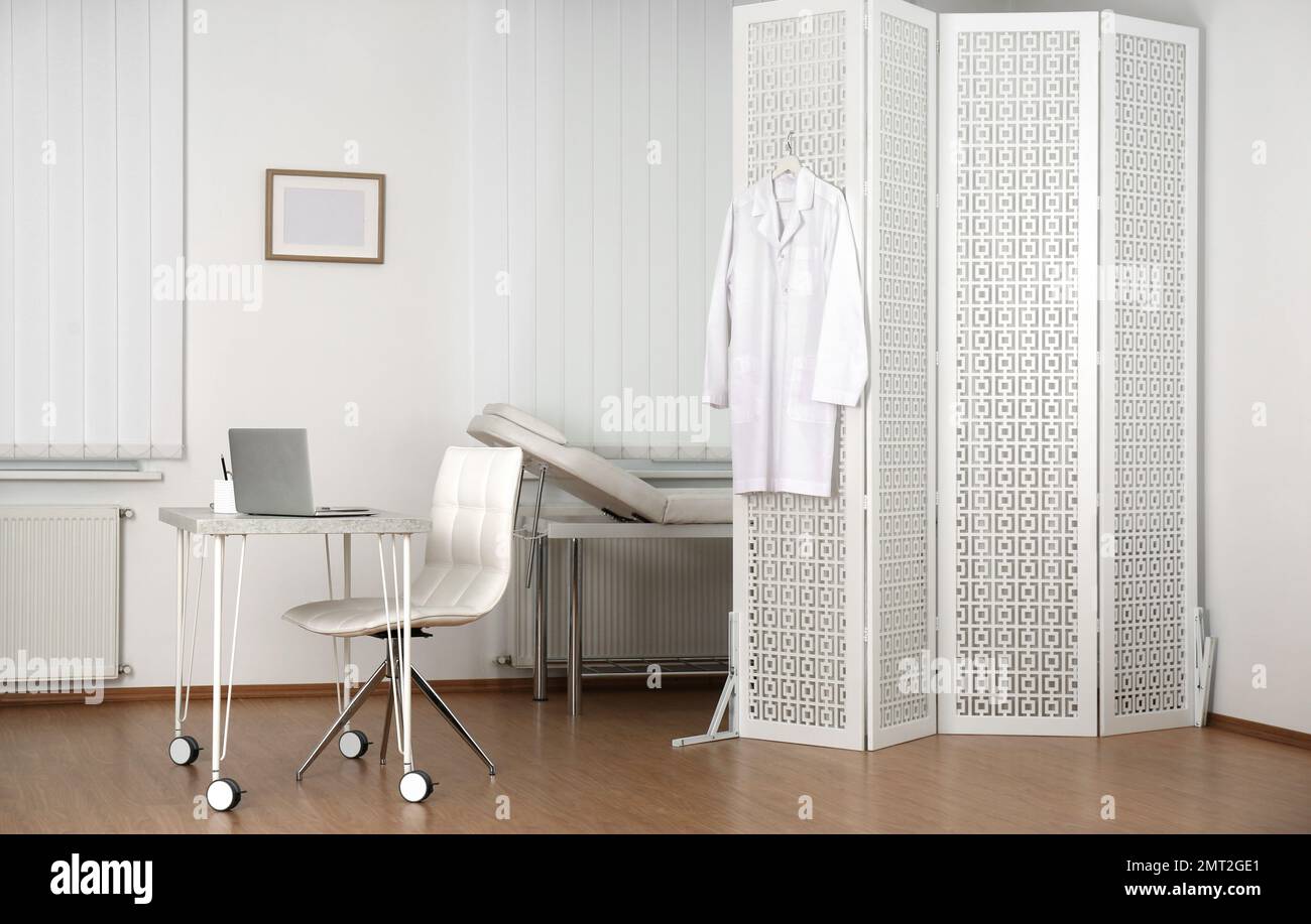 Doctor's office interior with desk, examination couch and folding ...
