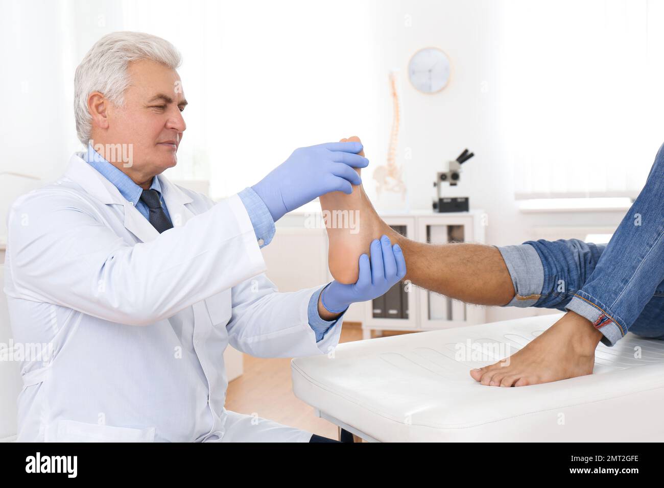 Male orthopedist checking patient's foot in clinic Stock Photo - Alamy