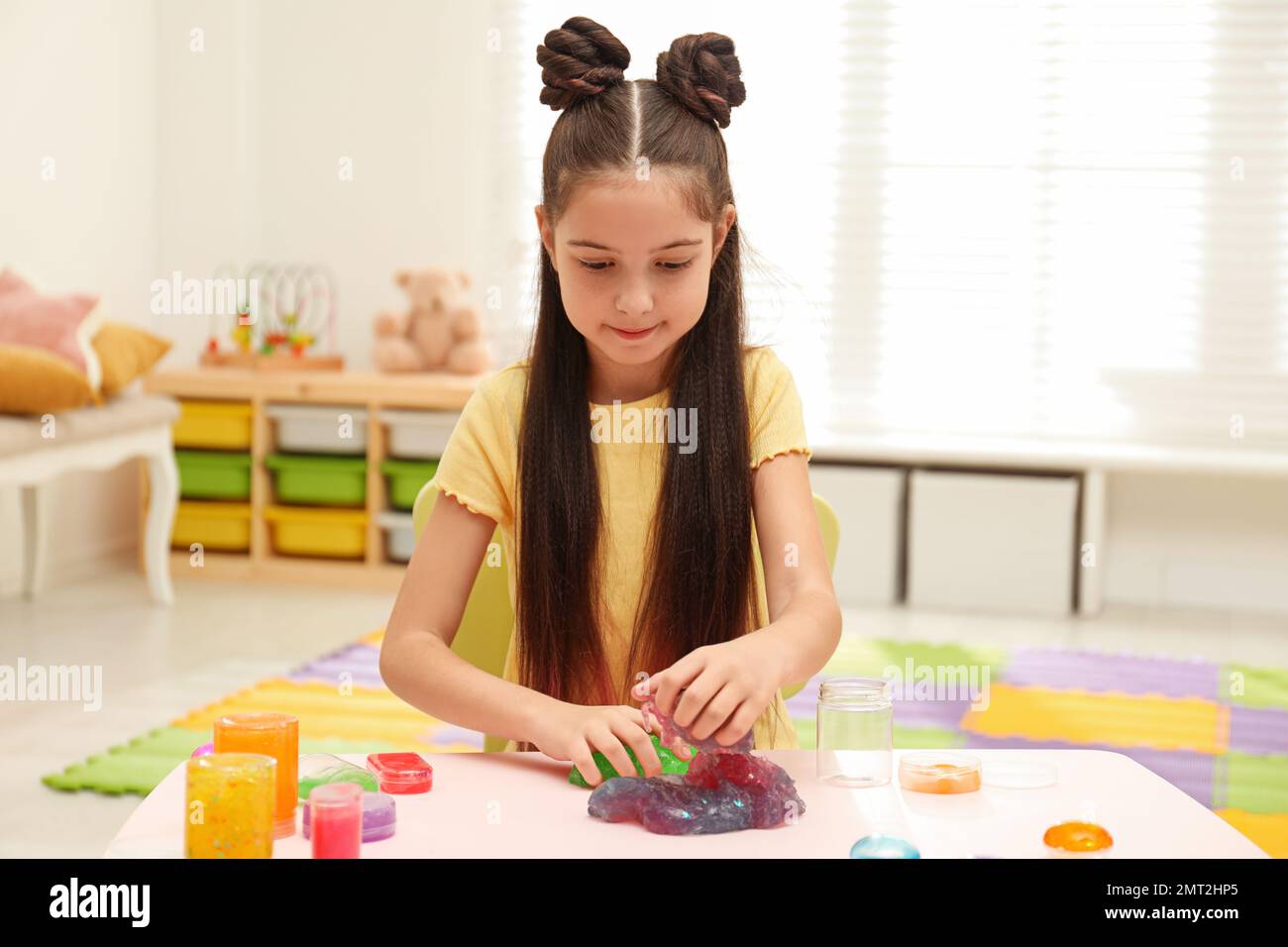 Little girl playing with slime at table indoors Stock Photo - Alamy